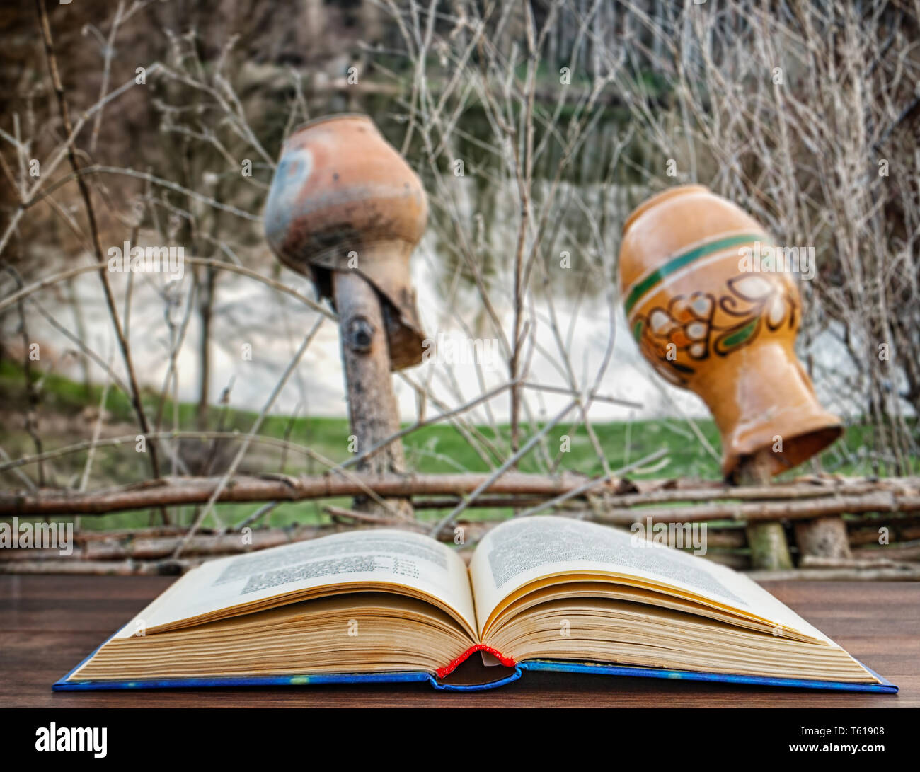 An open book on the background of an old fence with jugs and a lake ...