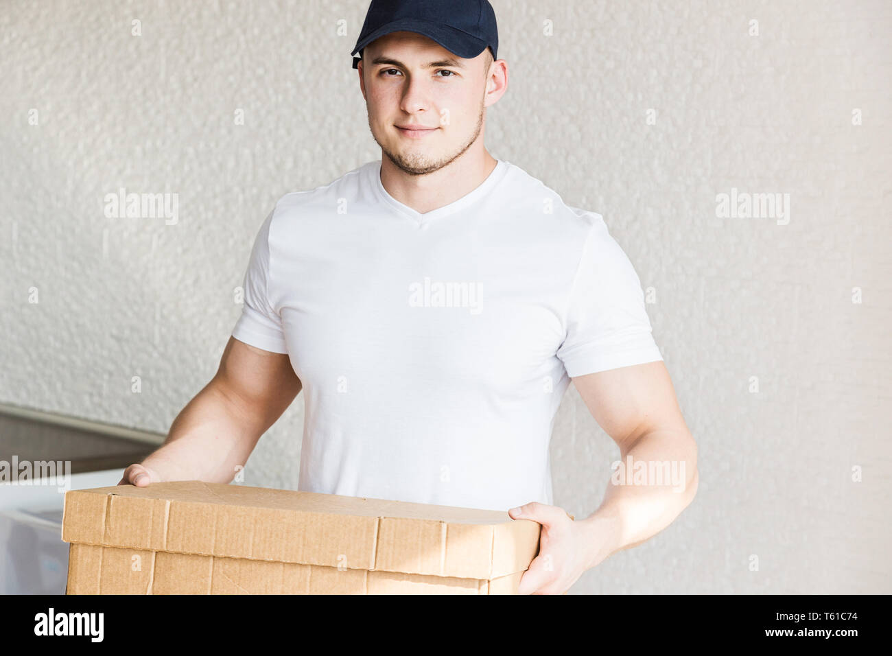 Delivery strong, muscular man loading cardboard boxes for moving to an ...