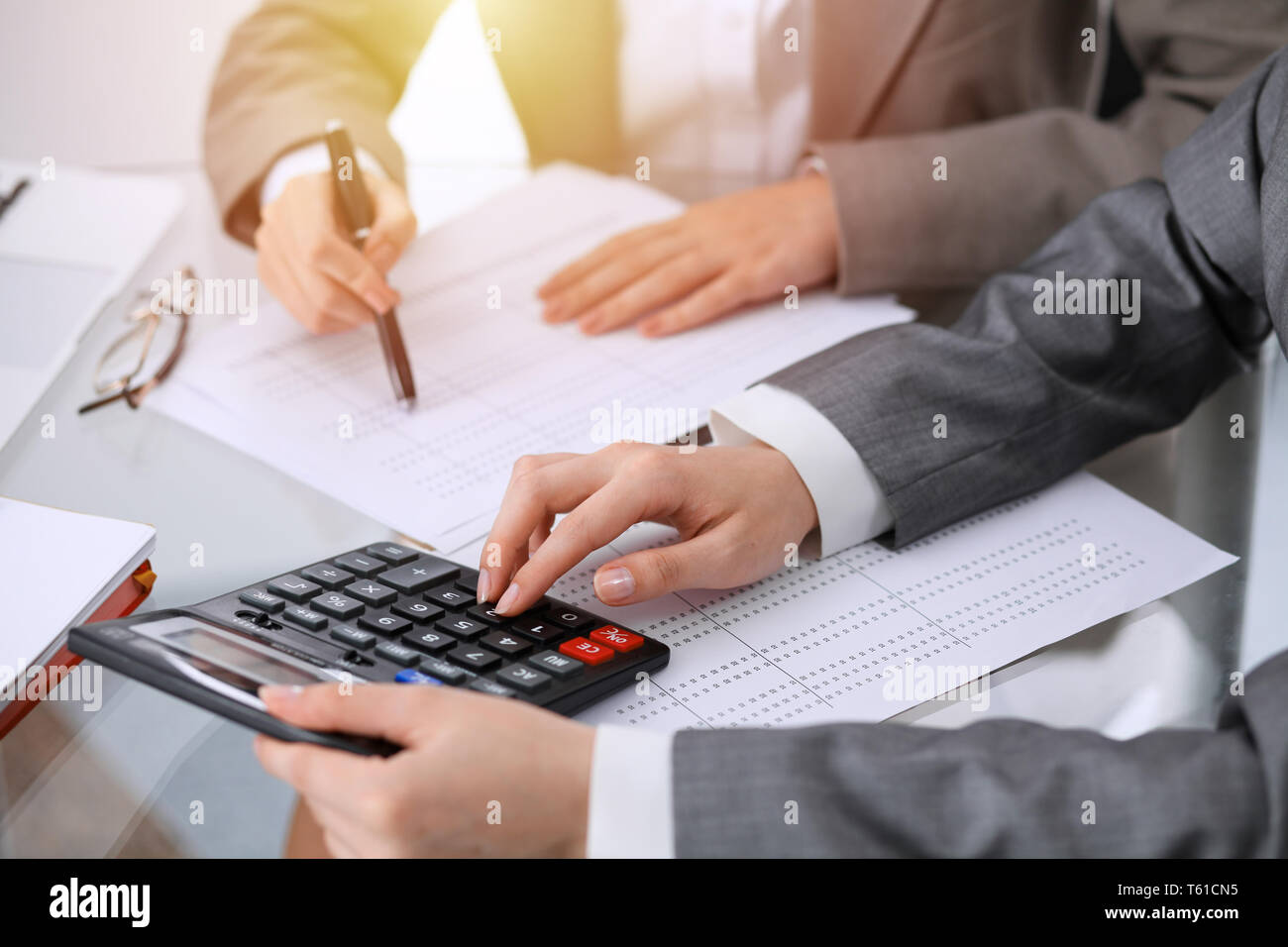 Two female accountants counting on calculator income for tax form ...