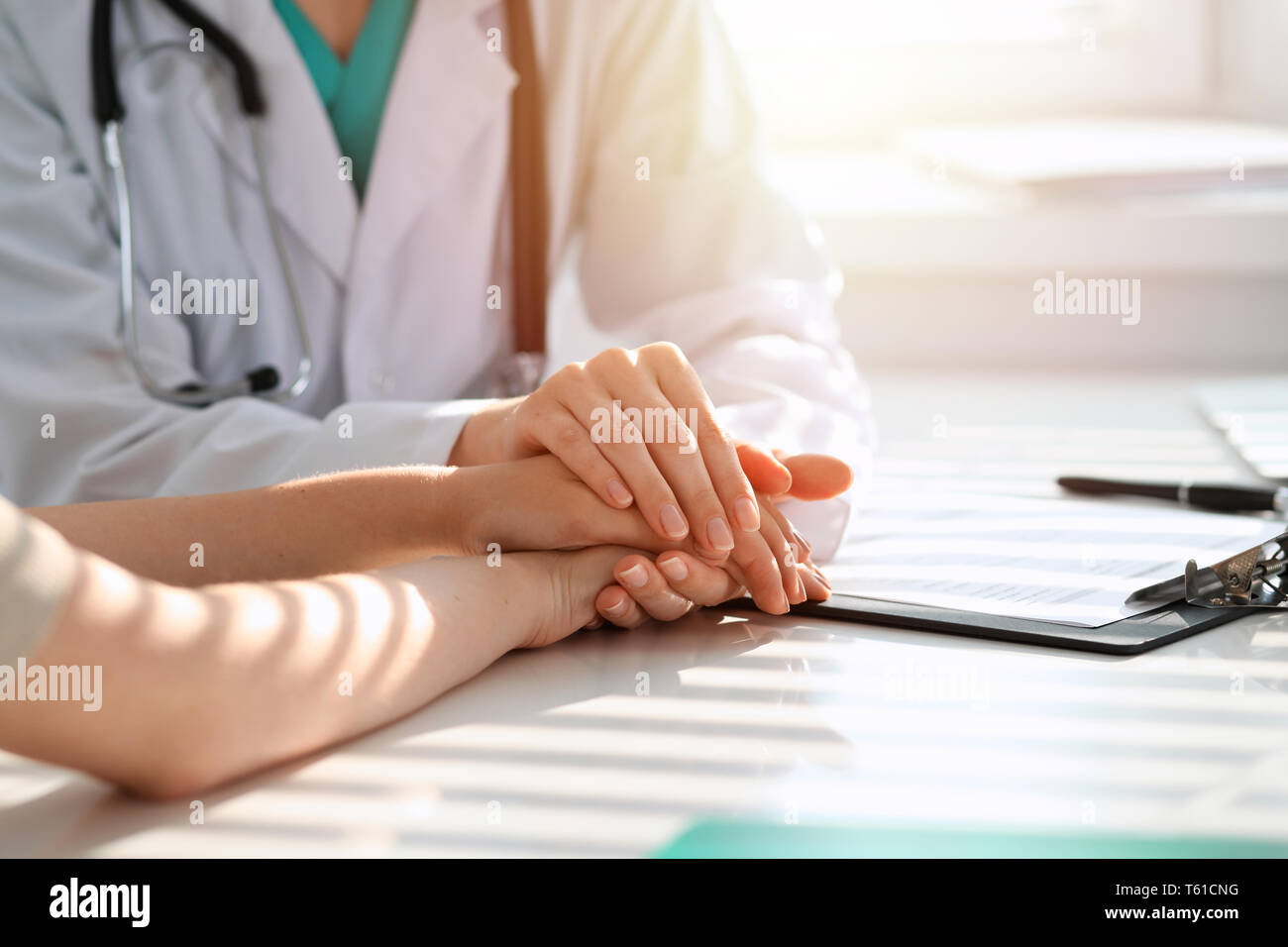 Doctor reassuring patient woman while sitting at the desk in clinic ...