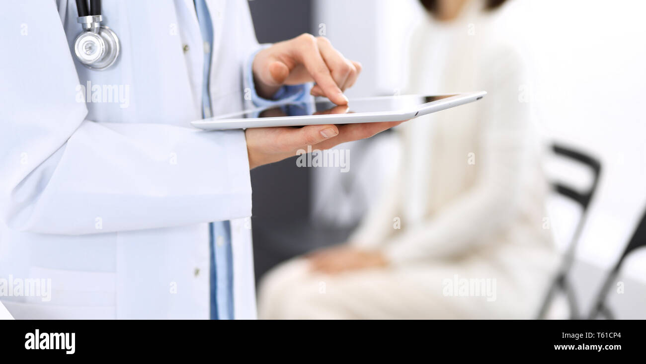 Female physician using digital tablet while standing near reception ...
