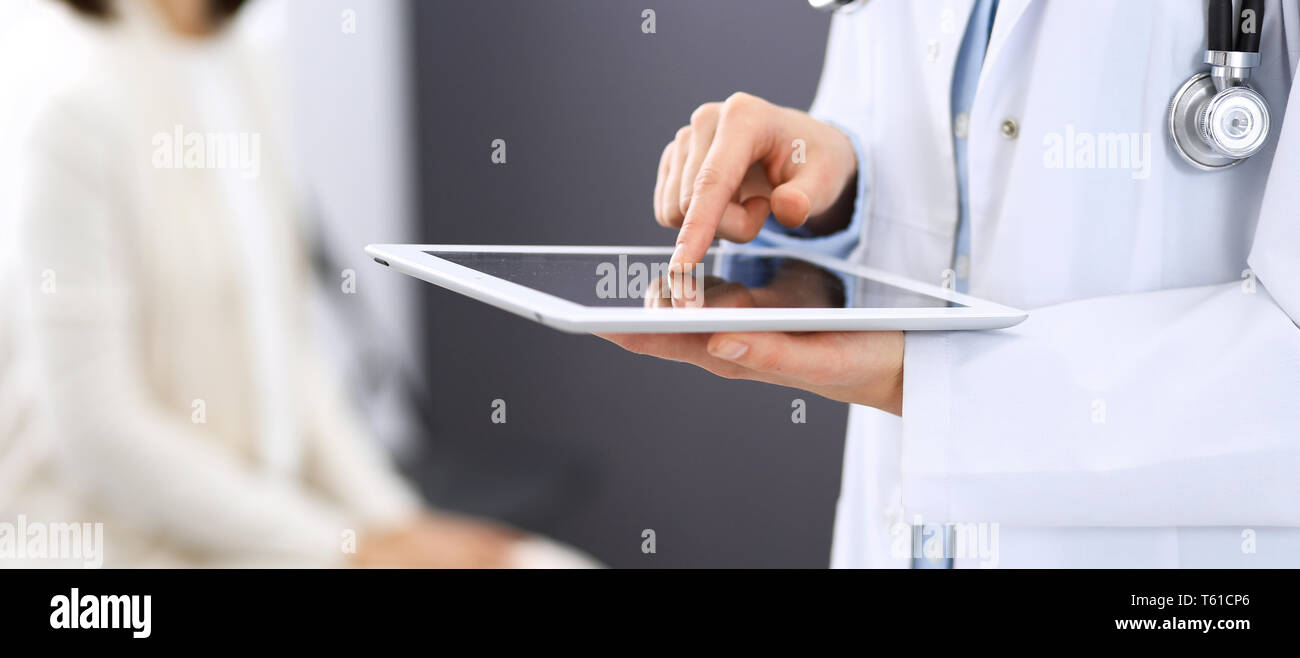 Female physician using digital tablet while standing near reception ...