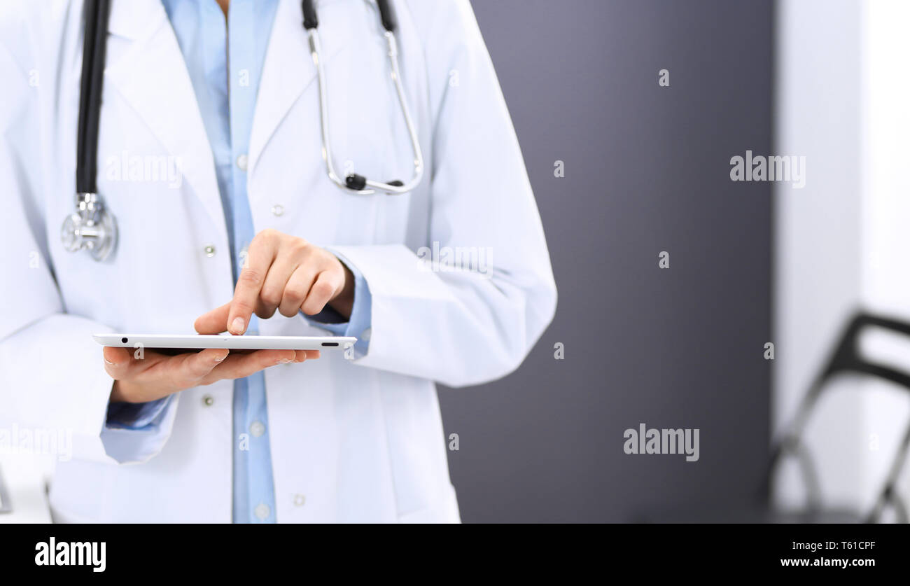 Female physician using digital tablet while standing near reception ...