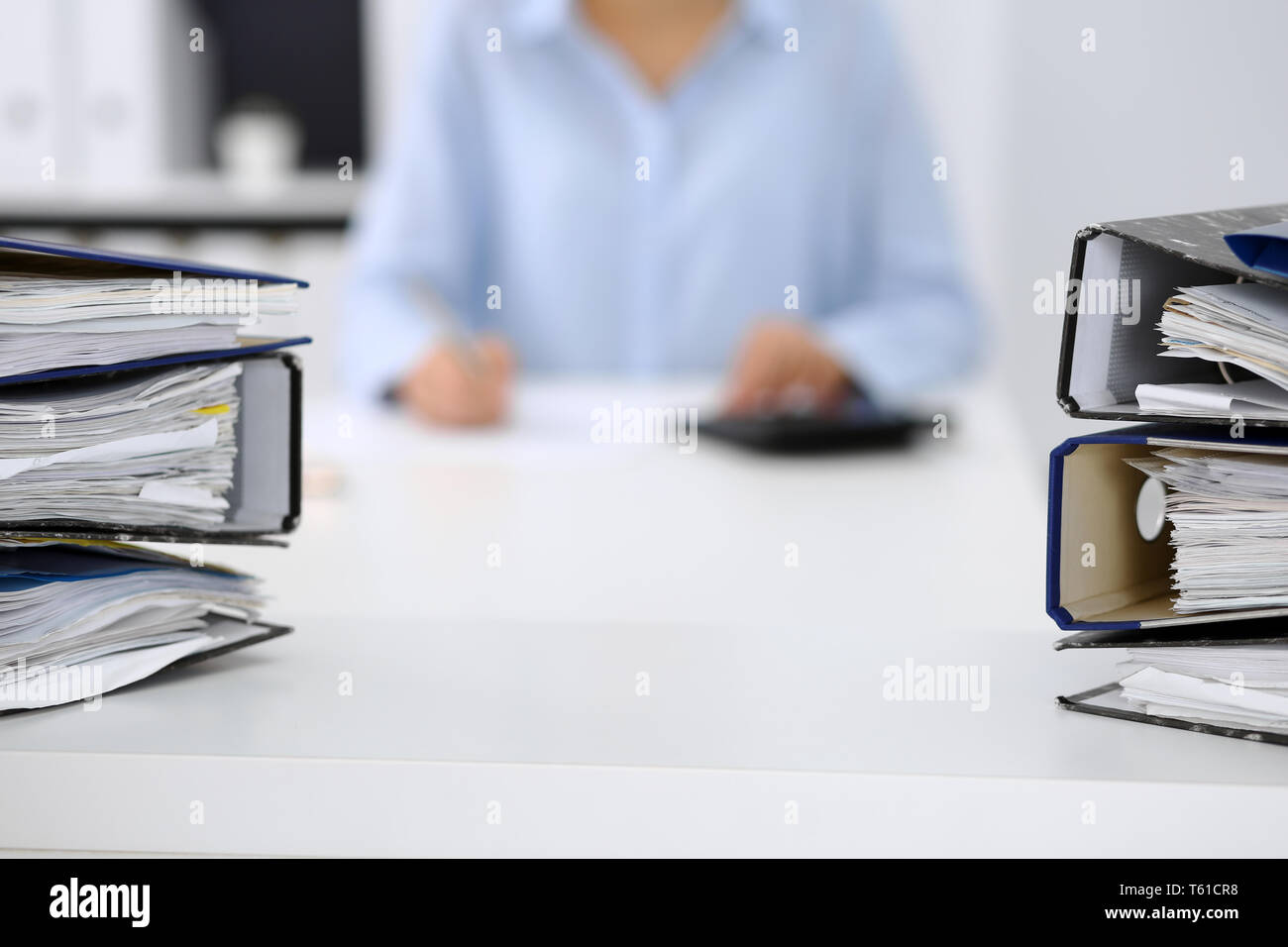 Binders with papers are waiting to be processed by business woman or ...