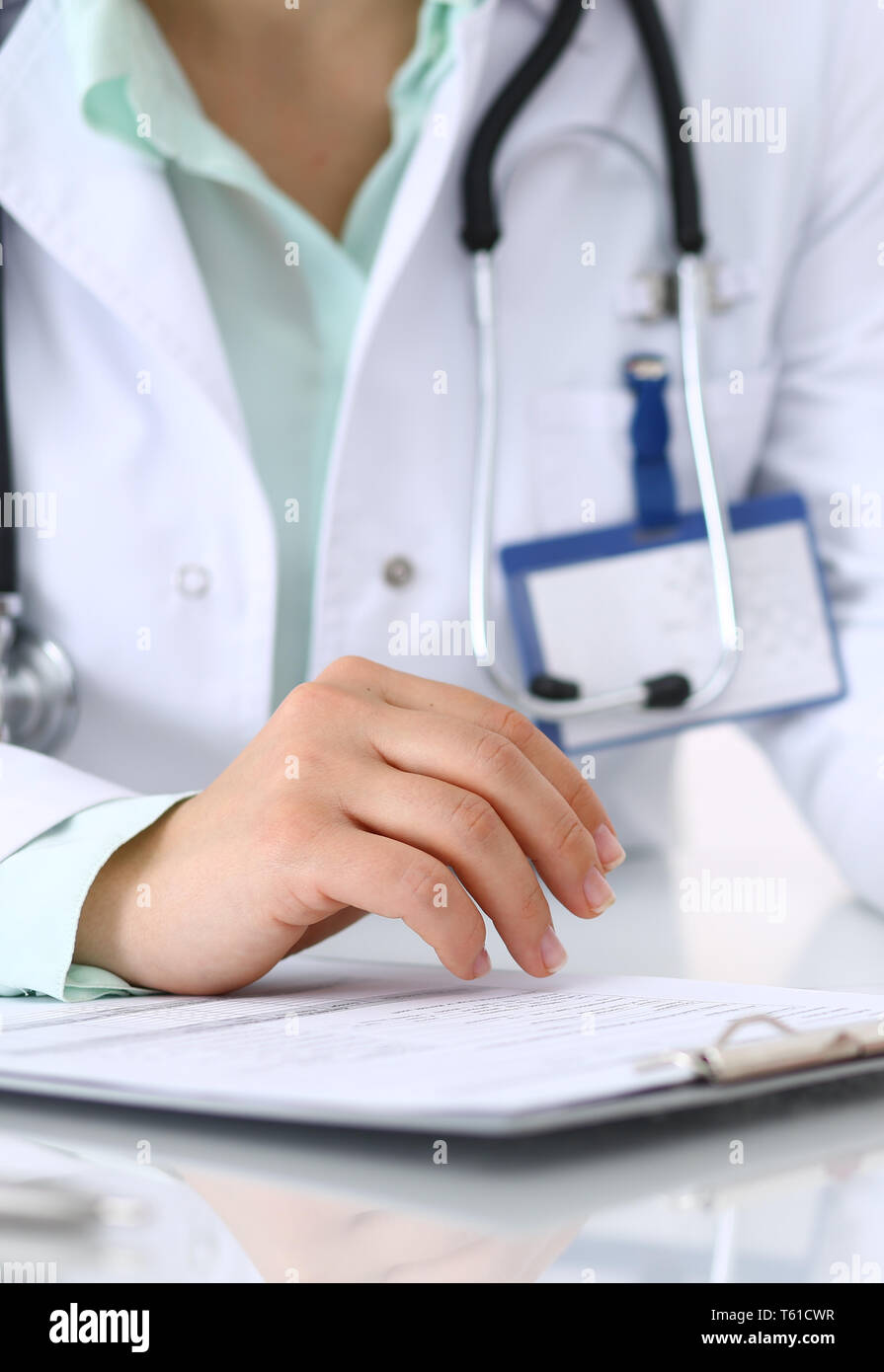 Unknown doctor and patient talking while sitting at the desk in ...