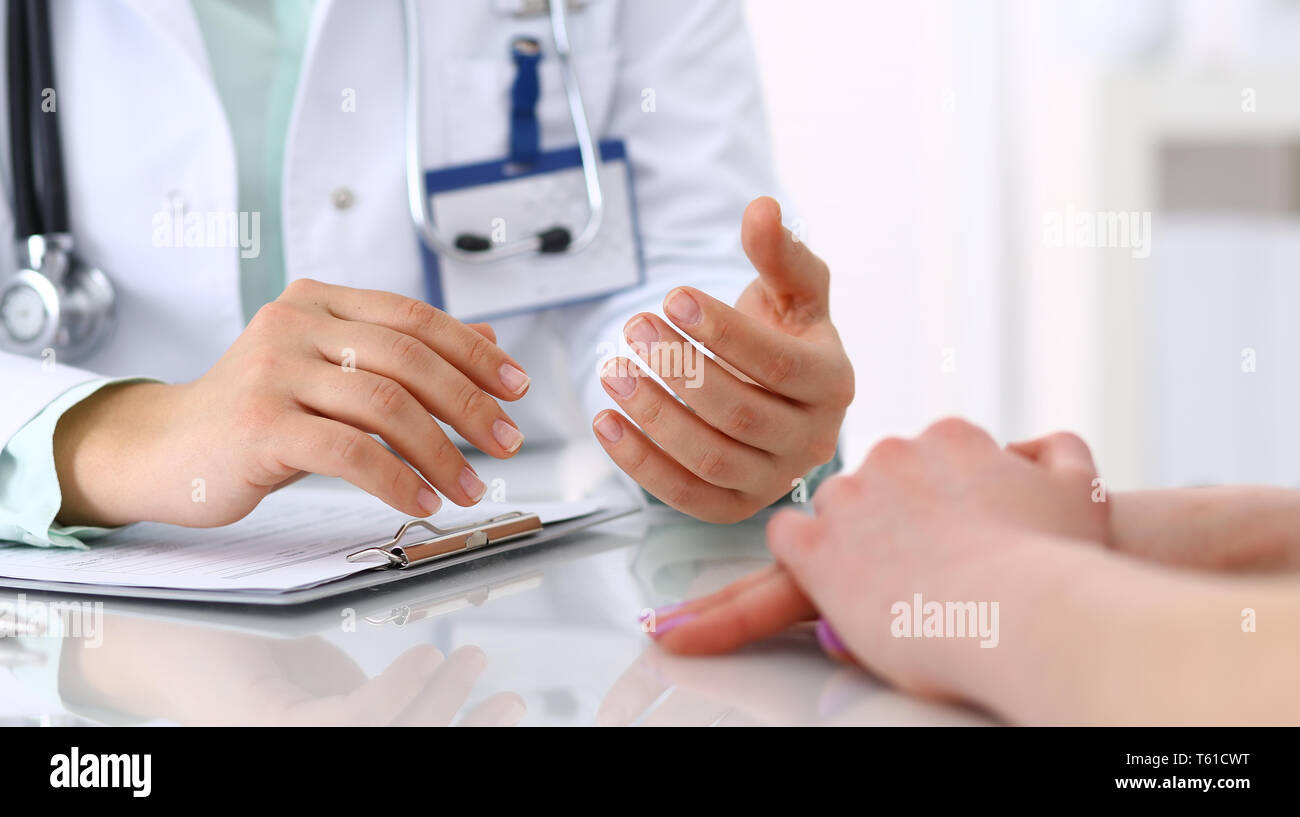 Unknown doctor and patient talking while sitting at the desk in ...