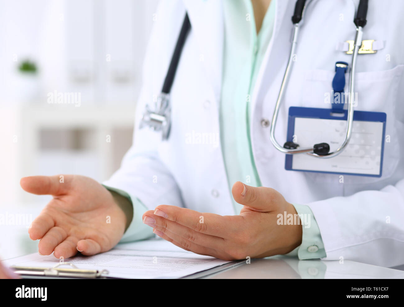 Unknown doctor and patient talking while sitting at the desk in ...