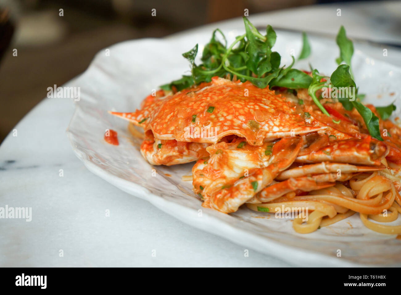 spicy boiled crab spaghetti on white disk with vegetable on top, ready ...