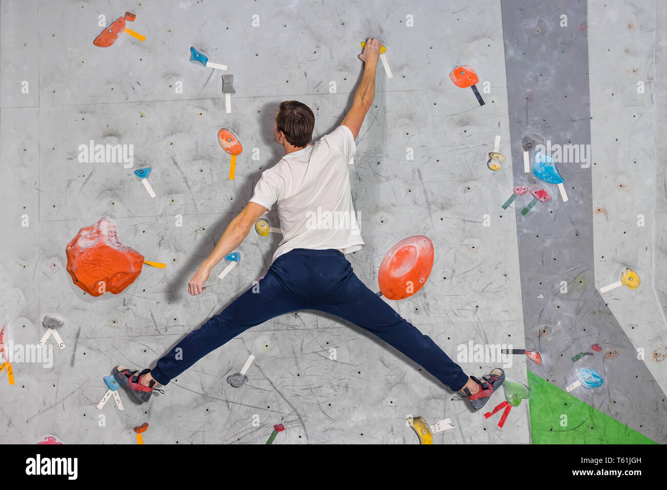 Climber man hanging in a twine on a climbing wall bouldering the wall ...
