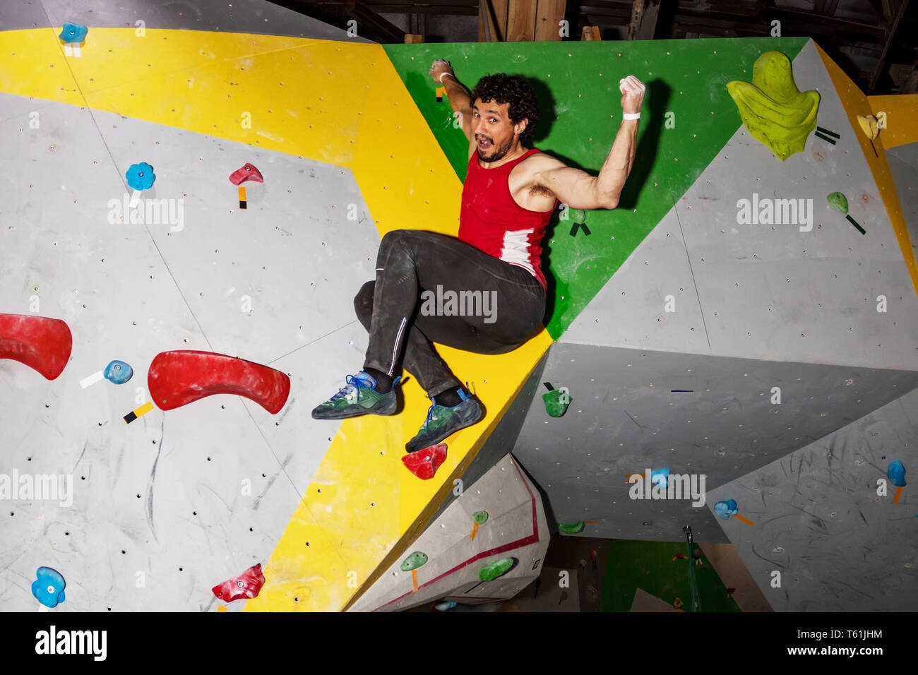 Rock climber man hanging on a bouldering climbing wall, inside on ...