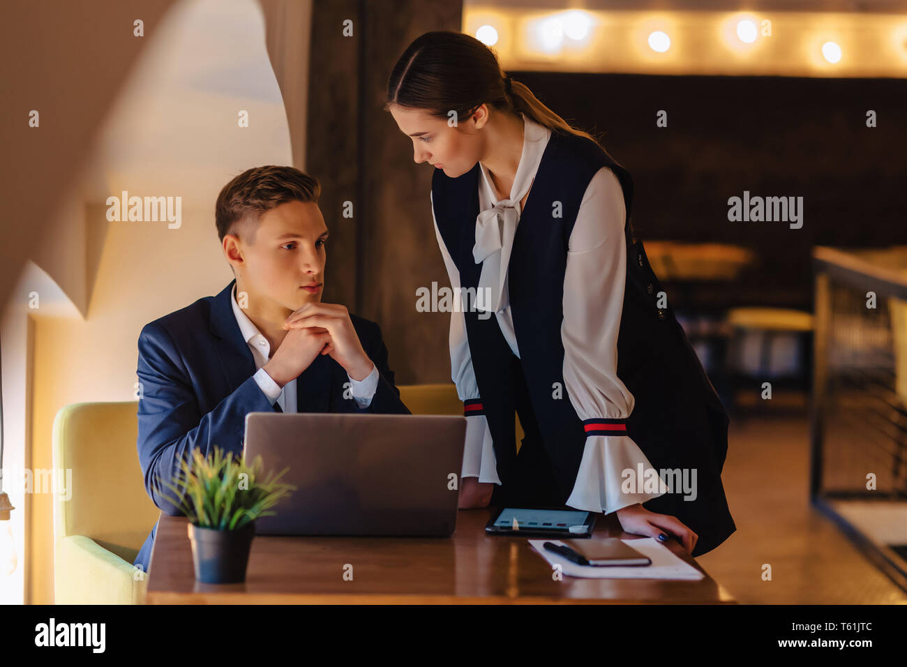 young businessmen boy and girl work with a laptop, a tablet and notes ...