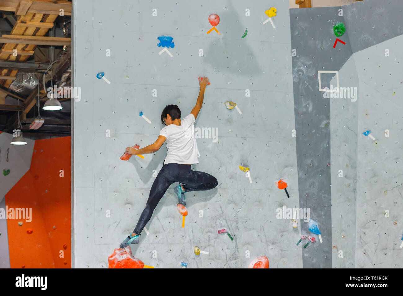 Rock climber woman hanging on a bouldering climbing wall, inside on ...