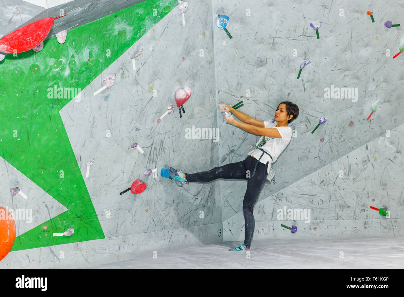 Rock climber woman hanging on a bouldering climbing wall, inside on ...