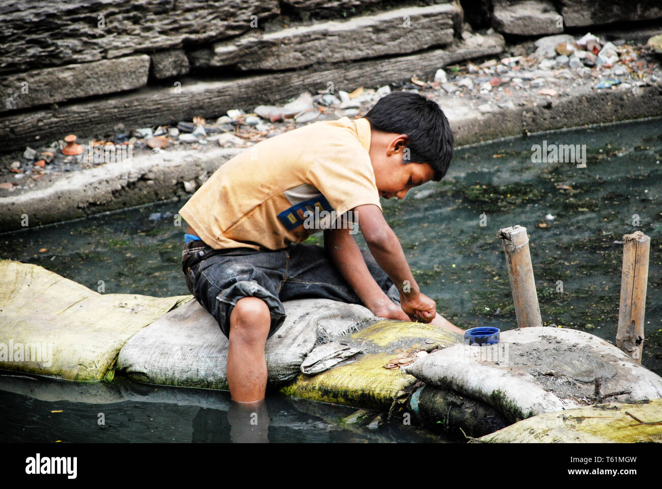 Kid collects coins in the Bagmati River, Kathmandu, Nepal. In Nepal, 25 ...