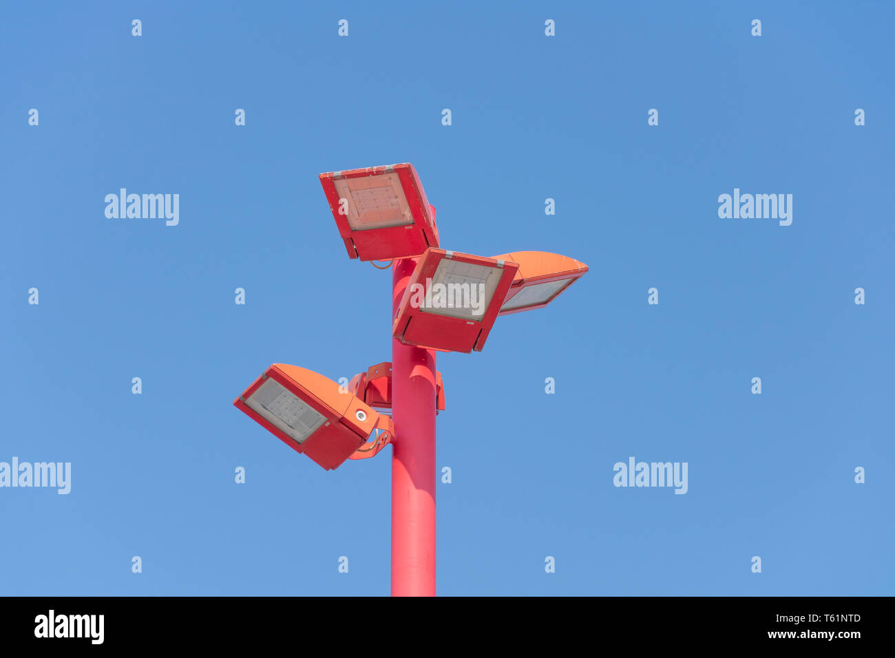 close up of a red led lighting pole with four lamps and a blue sky as ...