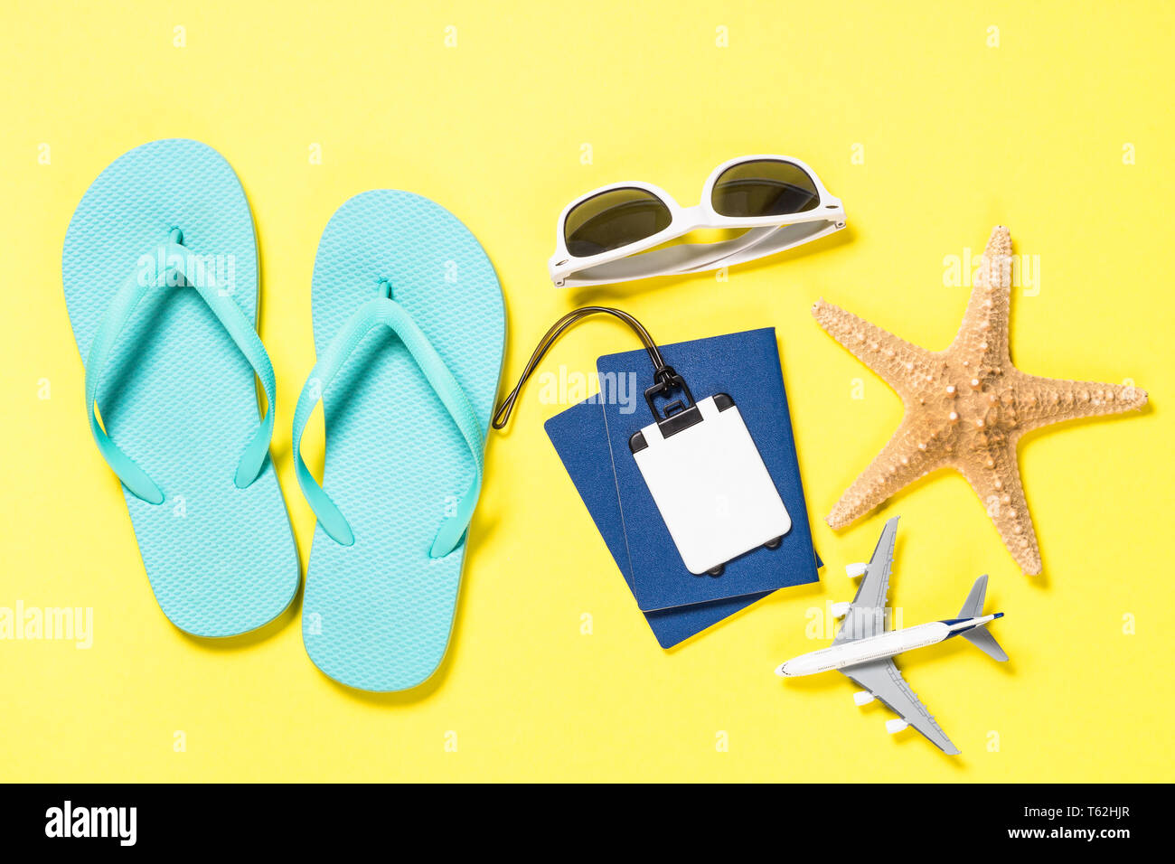 Blue flip flops, sunglasses, passport and starfish on yellow background ...