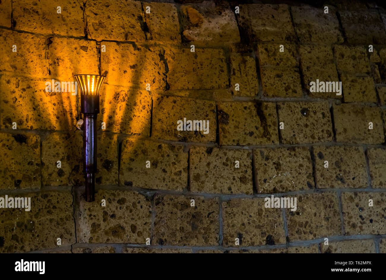 lighted medieval castle torch hanging on a stone wall, vintage objects ...