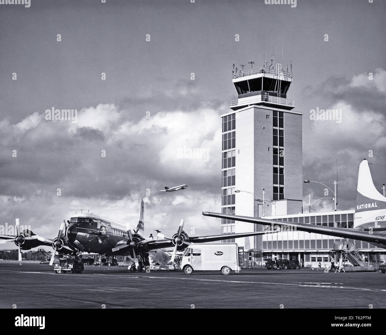 1960s AIR TRAFFIC CONTROL TOWER WITH AIRPLANES AND TRUCK IN FOREGROUND ...