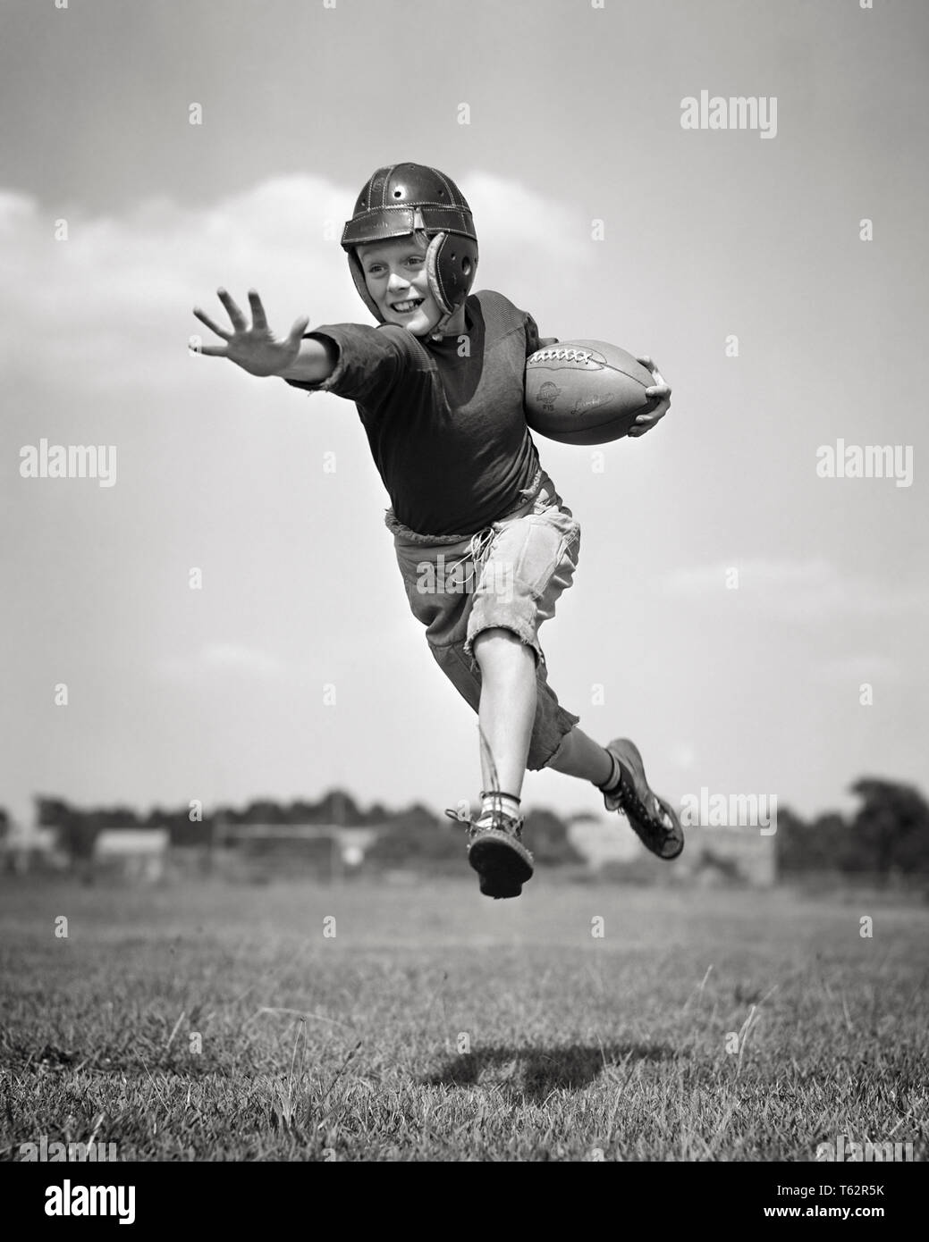1940s BOY WEARING HELMET FOOTBALL UNIFORM RUNNING CARRYING BALL BOTH ...