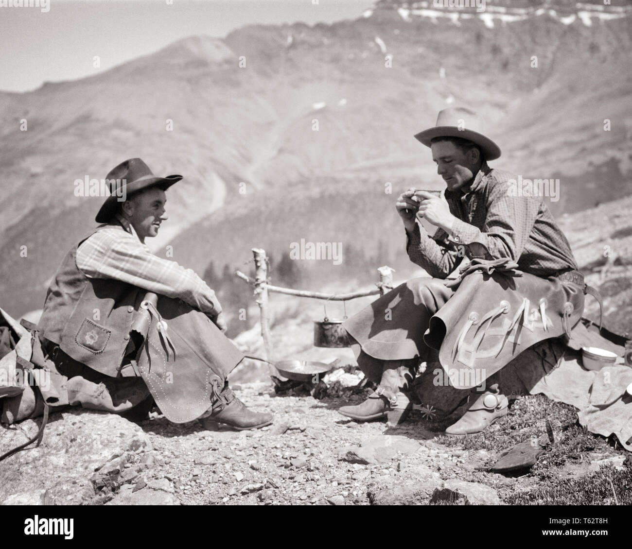 1920s 1930s TWO MEN WESTERN COWBOYS SITTING BY CAMPFIRE DRINKING COFFEE ...