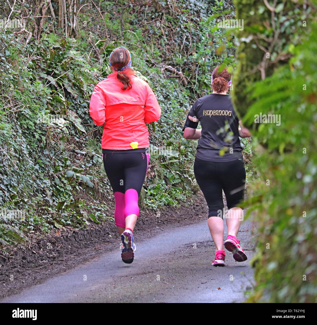 Two women jogging down a country lane Stock Photo - Alamy