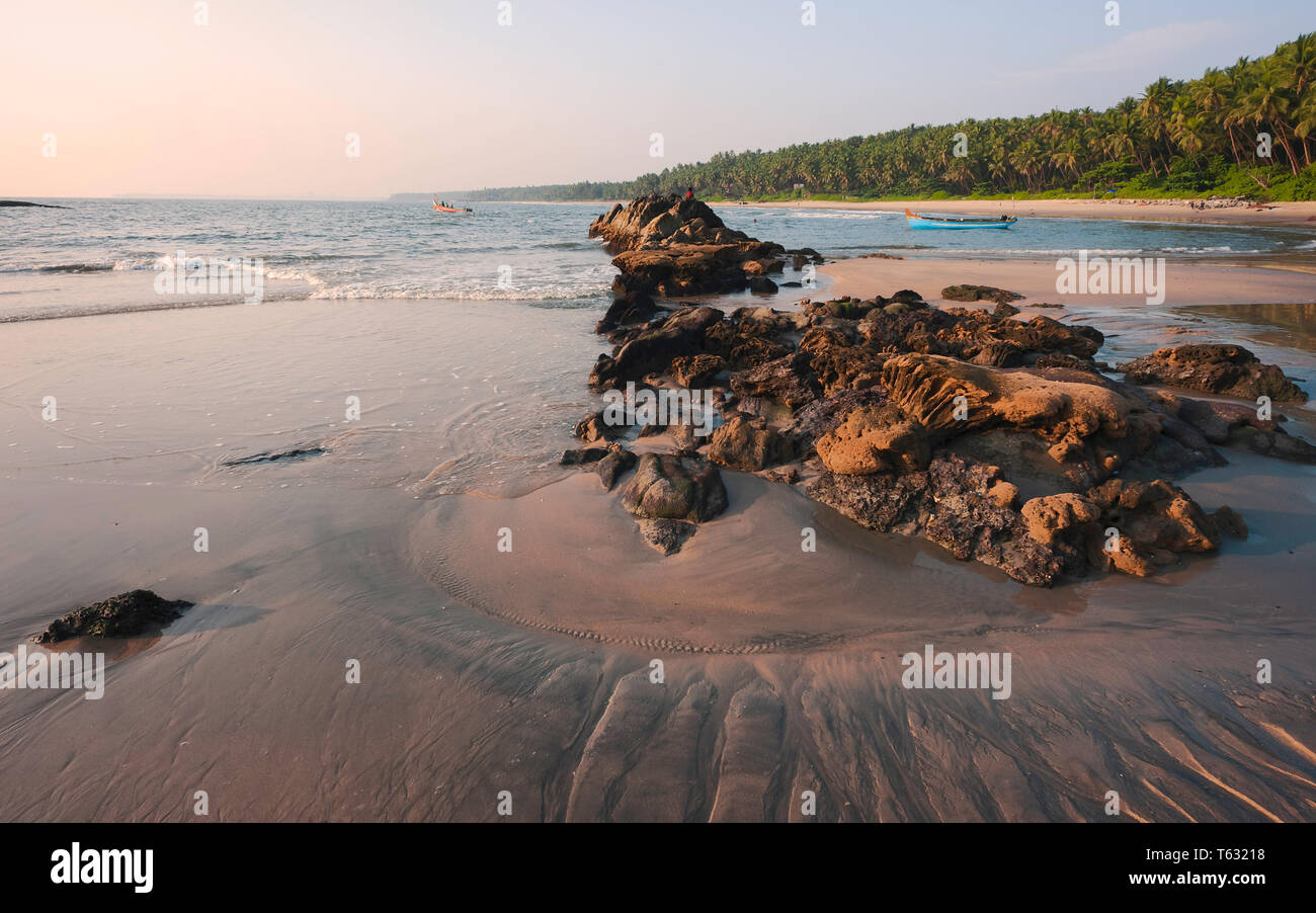 Chera rock in midst of sandy palm-lined beach and wooden boat ...