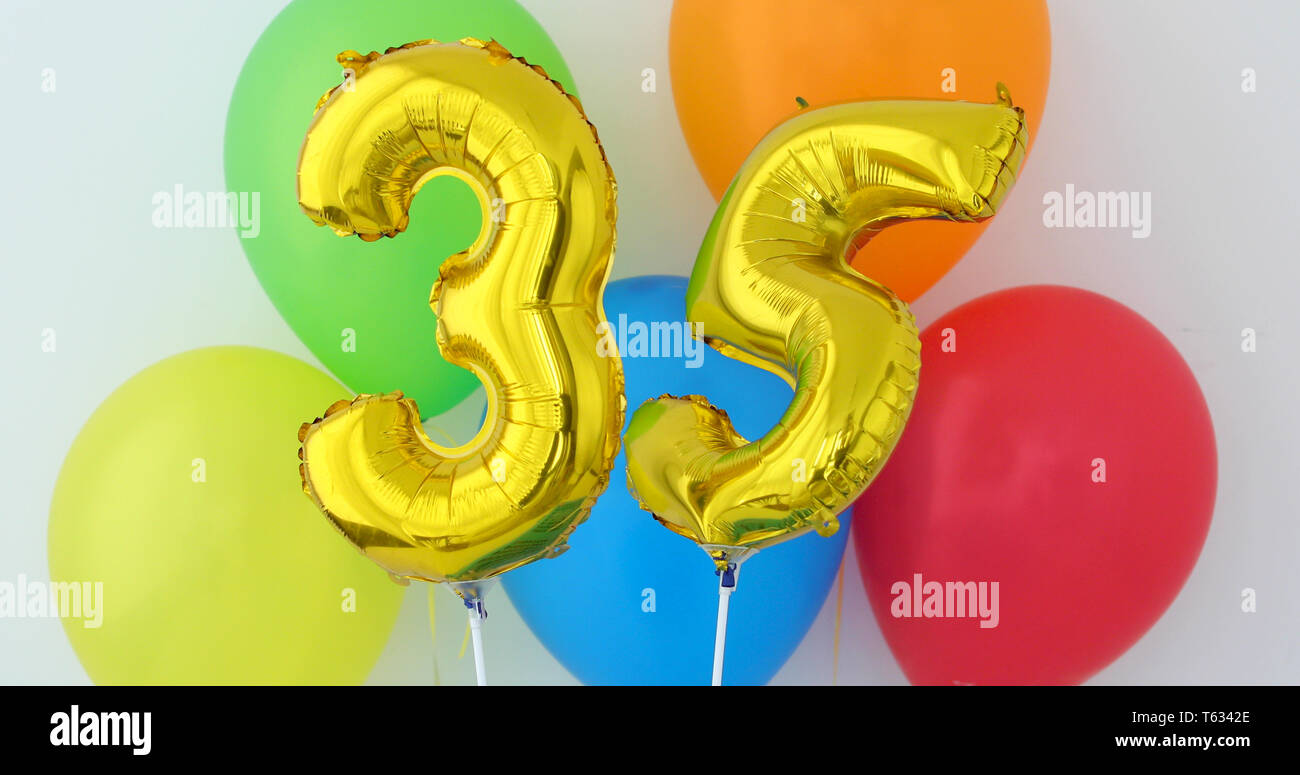 Gold foil number 35 celebration balloon on a color Stock Photo - Alamy