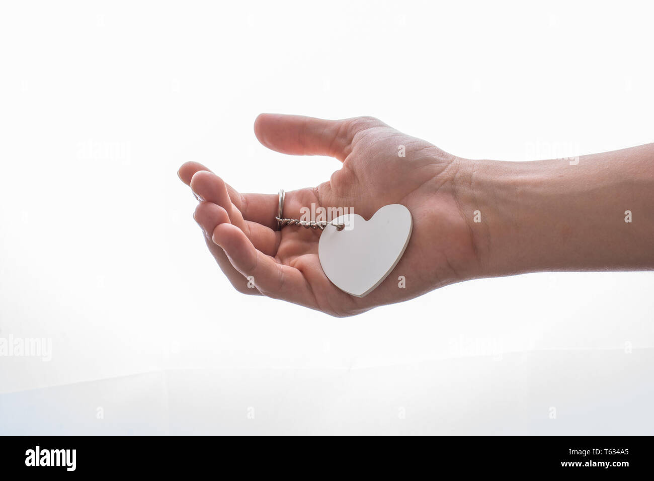 Heart shaped white object in hand on white background Stock Photo - Alamy