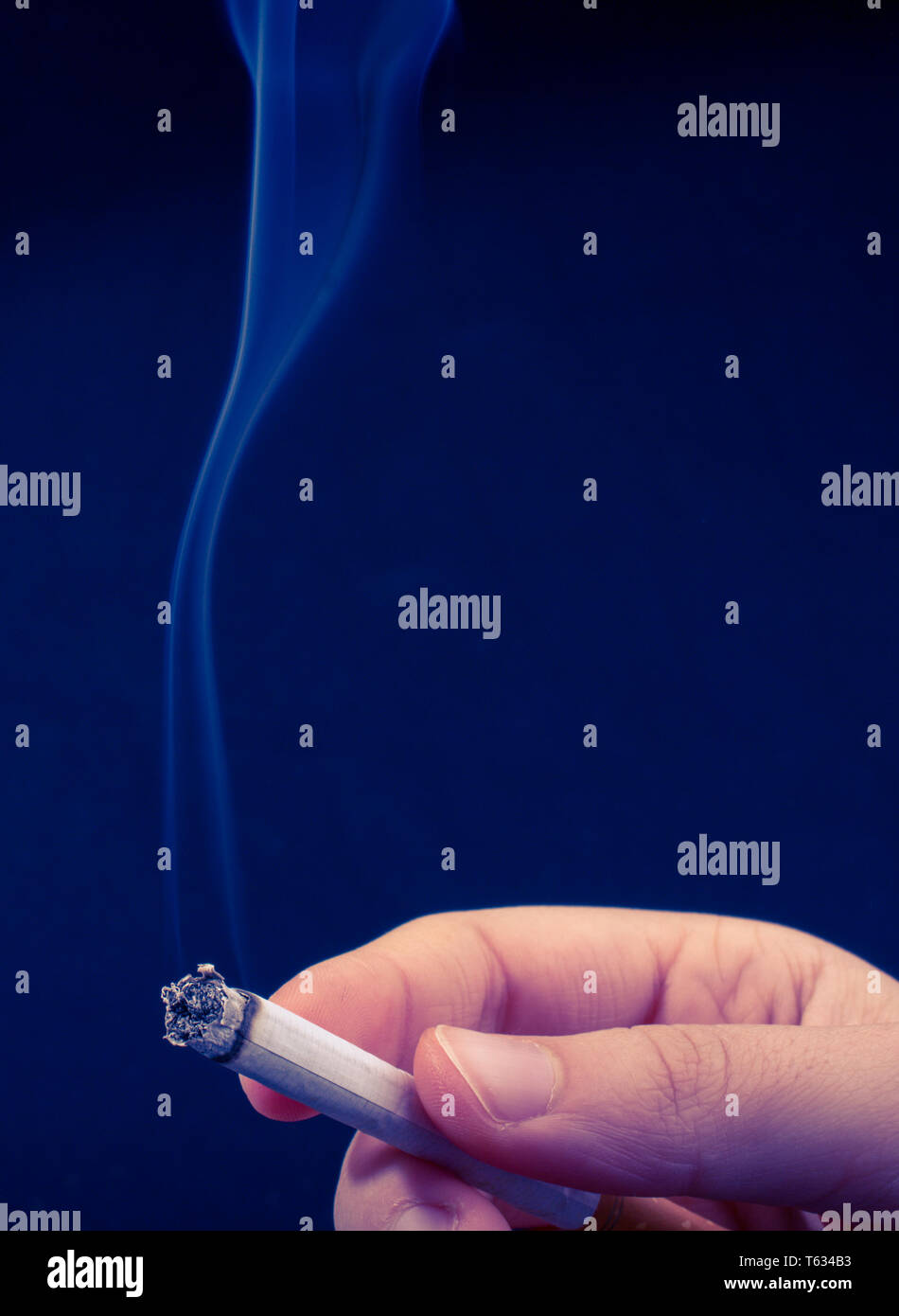Hand is holding smoking cigarette with smoke around Stock Photo - Alamy