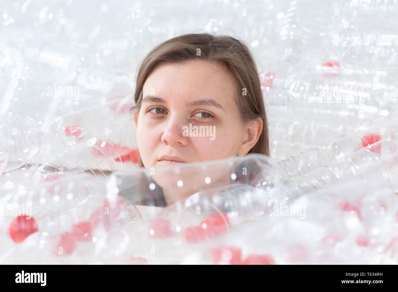 Dehydrated sick woman is lying in a pile of plastic bottles ...