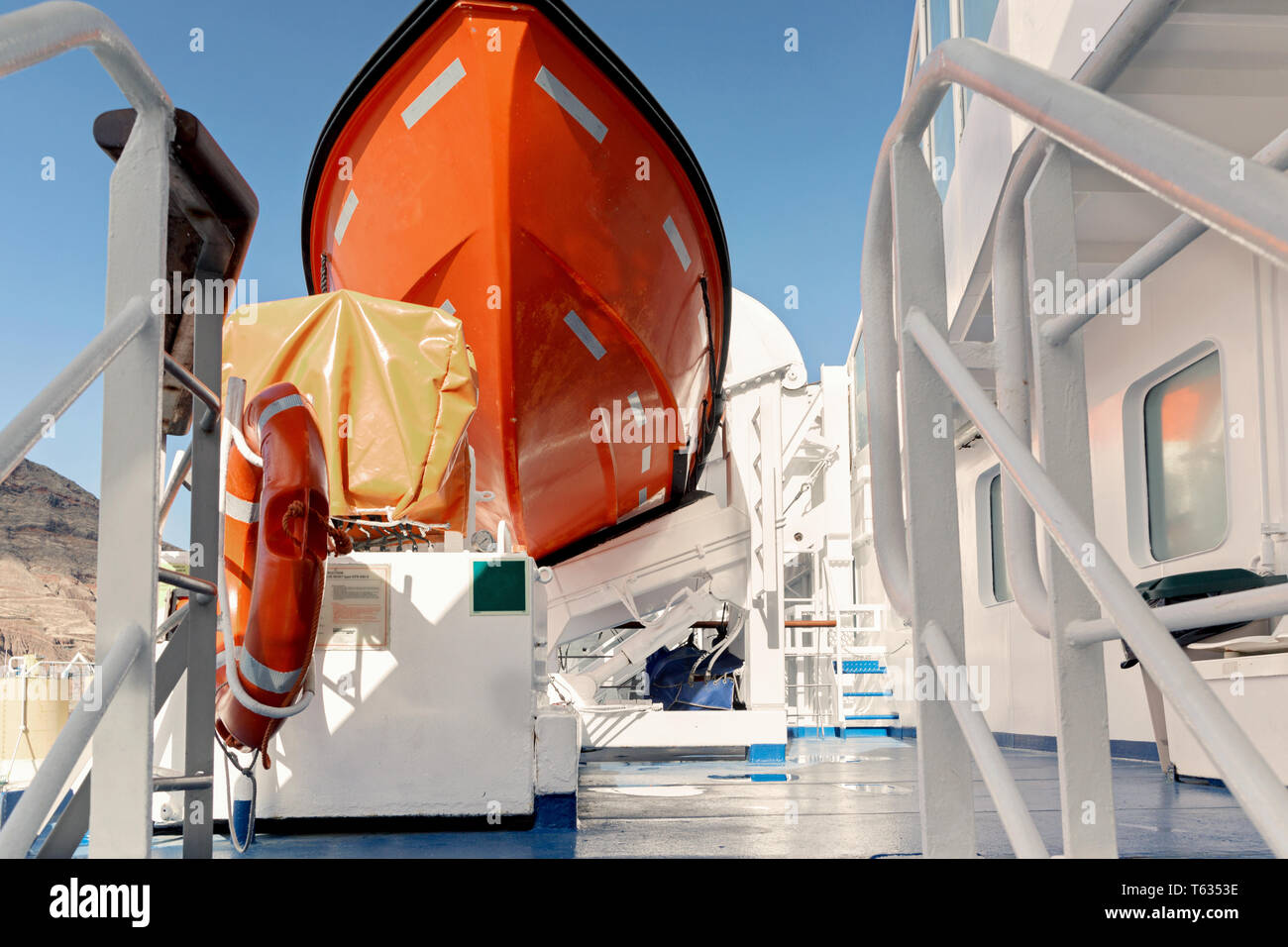 Orange lifeboat hangs on board, top down view. White steps and ...