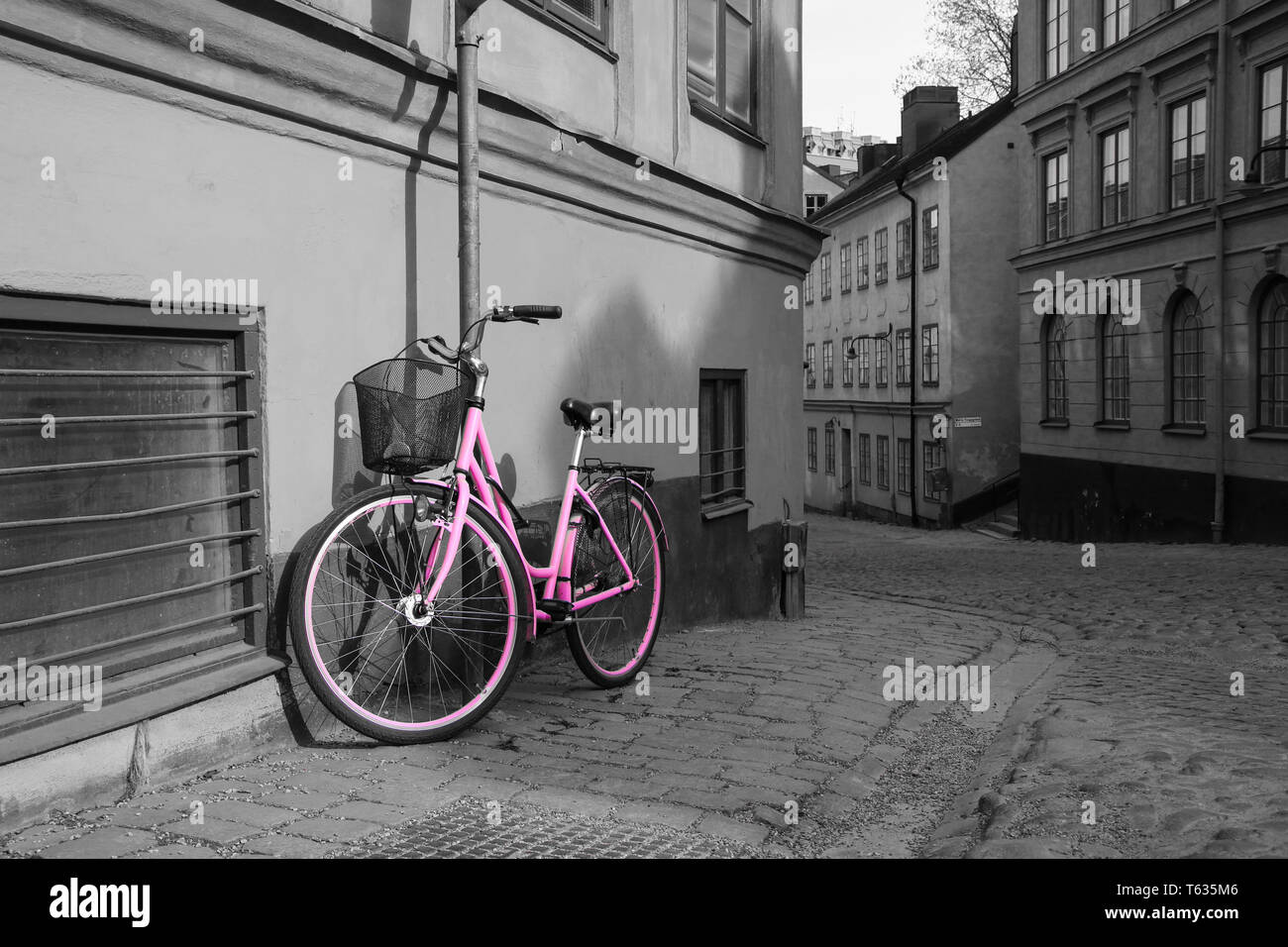 A picture of a lonely pink bike standing in the typical street in Stockholm The bike looks to be ...