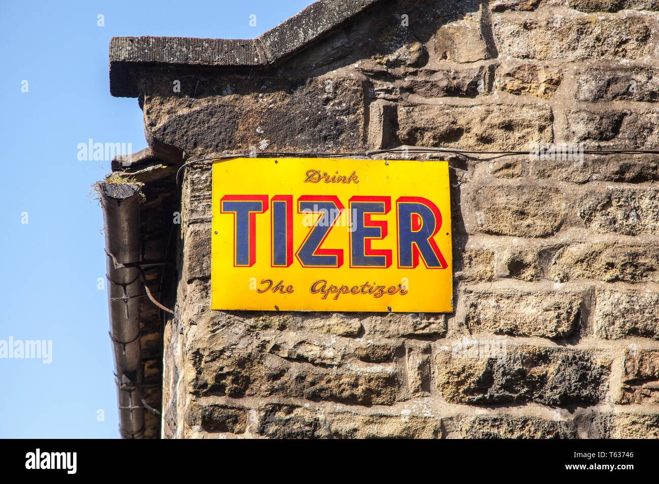 Old metal Advertising sign for the soft drink Tizer on a wall in the ...