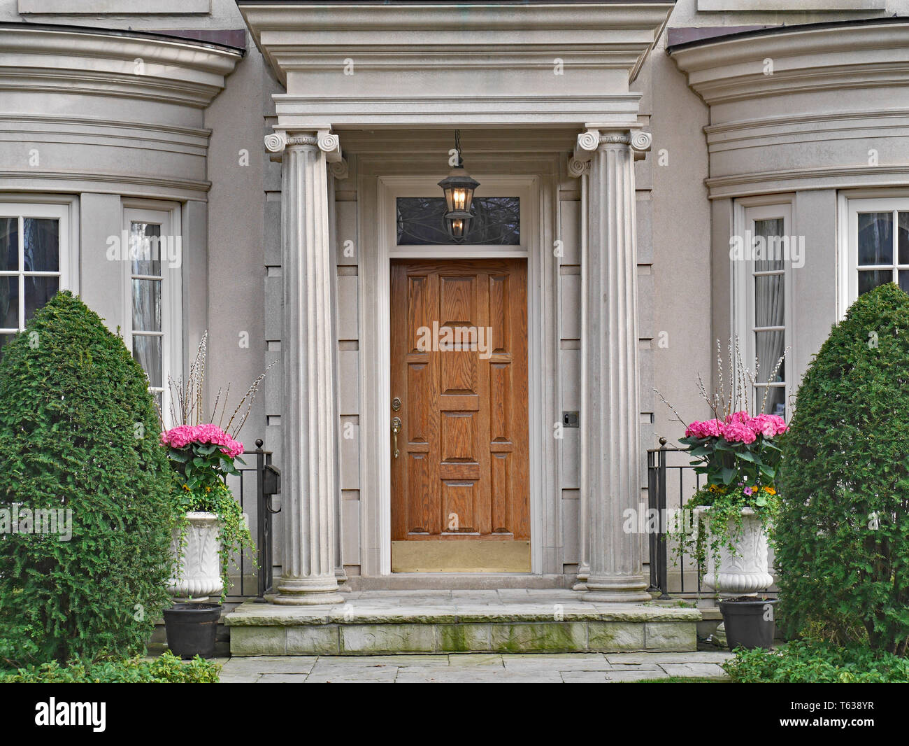front of elegantly landscaped house with stone column portico over ...