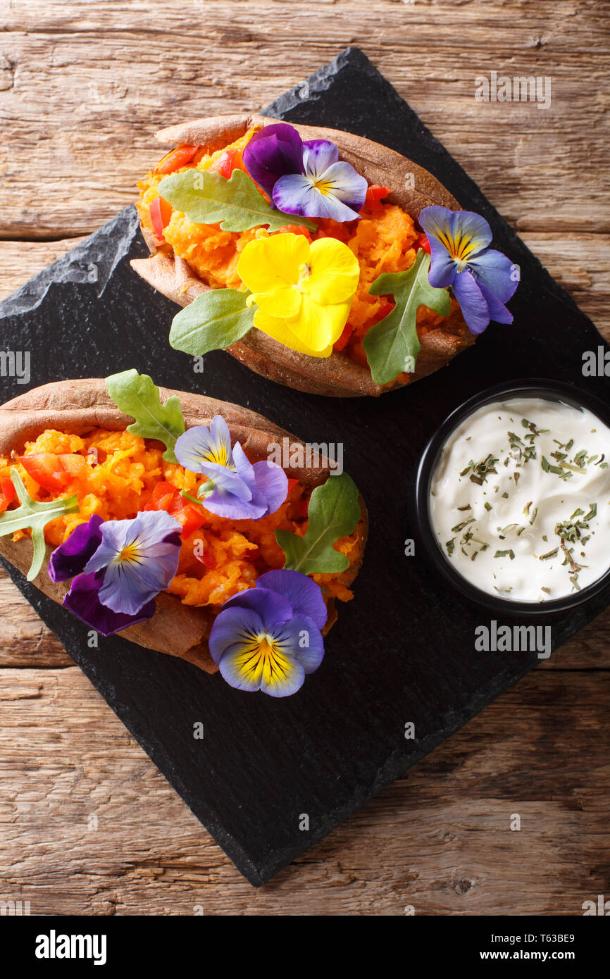 Baked yam with cream cheese decorated with edible flowers close-up on ...