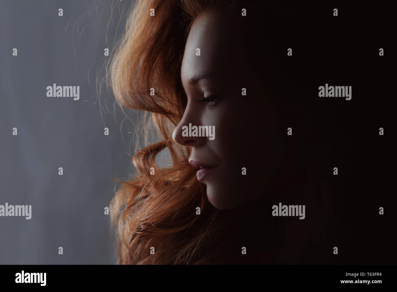 Young beautiful woman profile portrait in dark key. Empty space for ...
