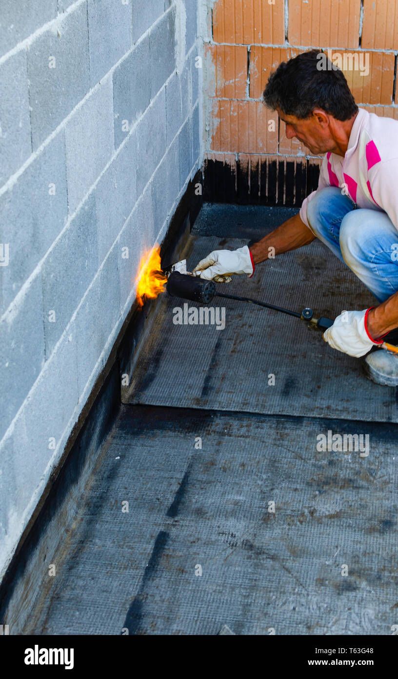Flat roof installation. Heating and melting bitumen roofing felt Stock Photo - Alamy