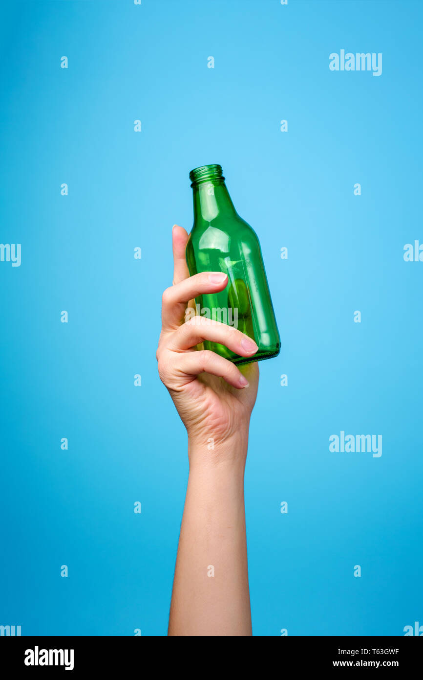 hand holding glass bottle on blue background Stock Photo - Alamy