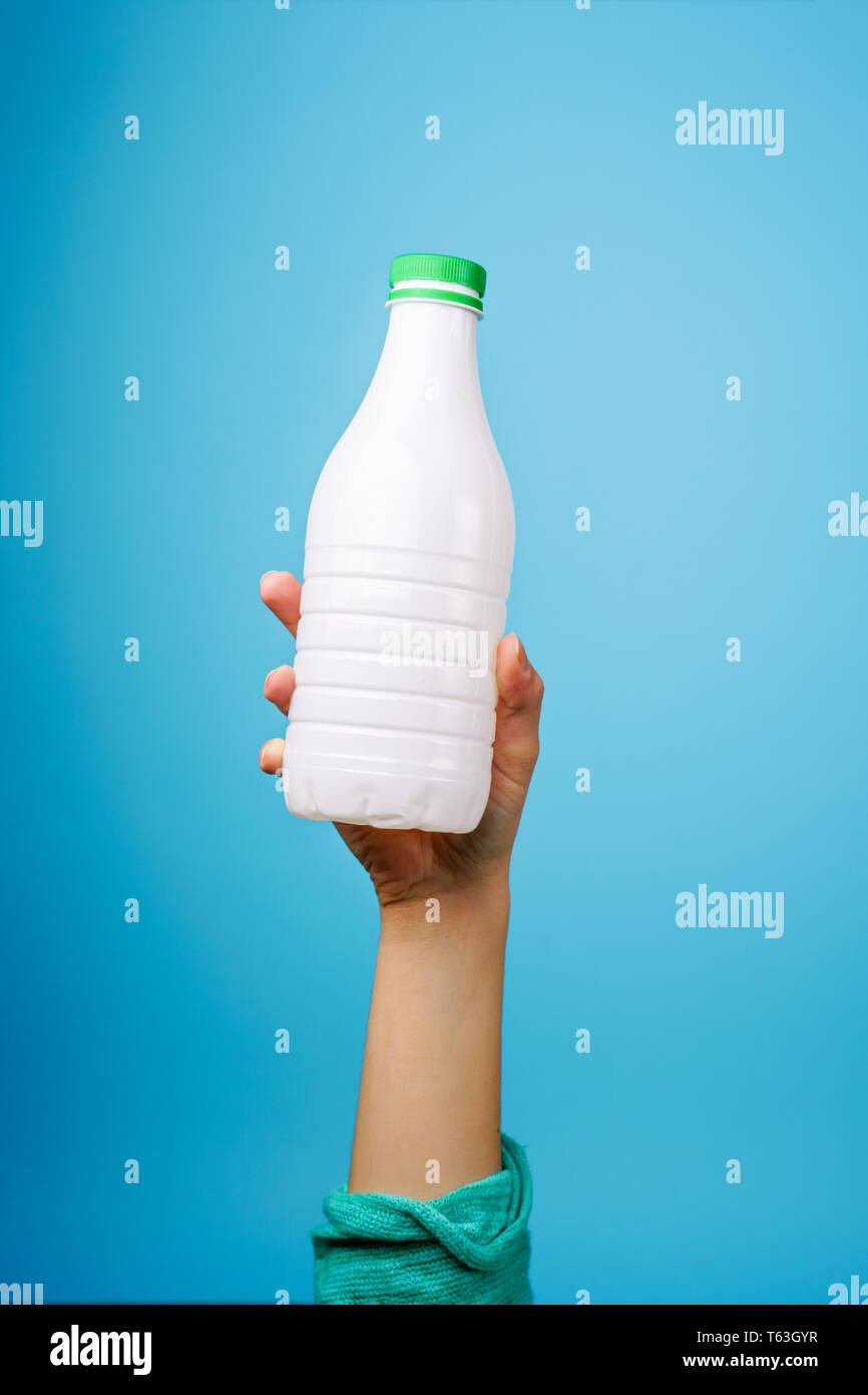 Plastic bottle in hand against blue background Stock Photo - Alamy