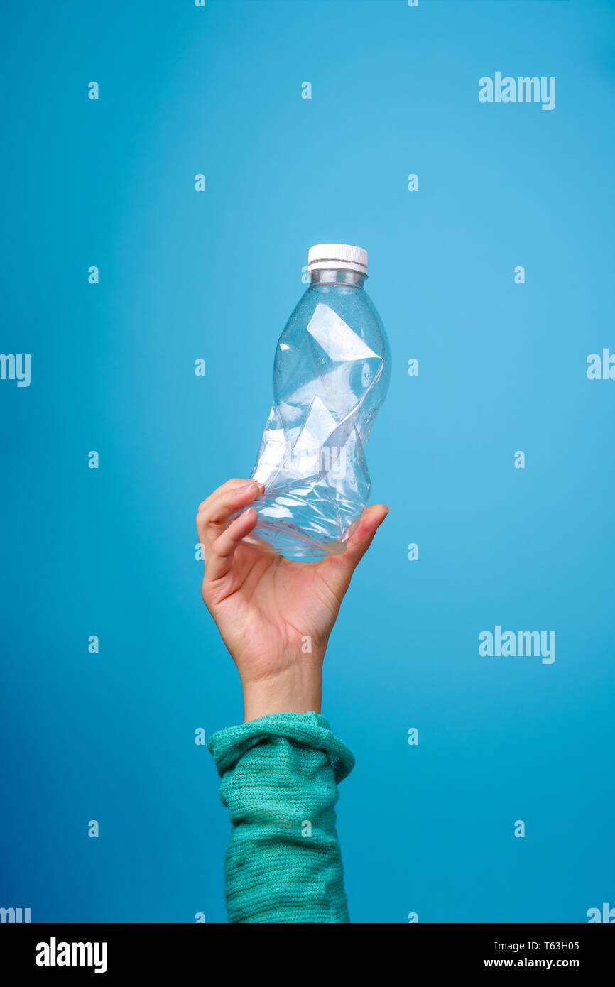 Plastic bottle in hand against blue background Stock Photo - Alamy