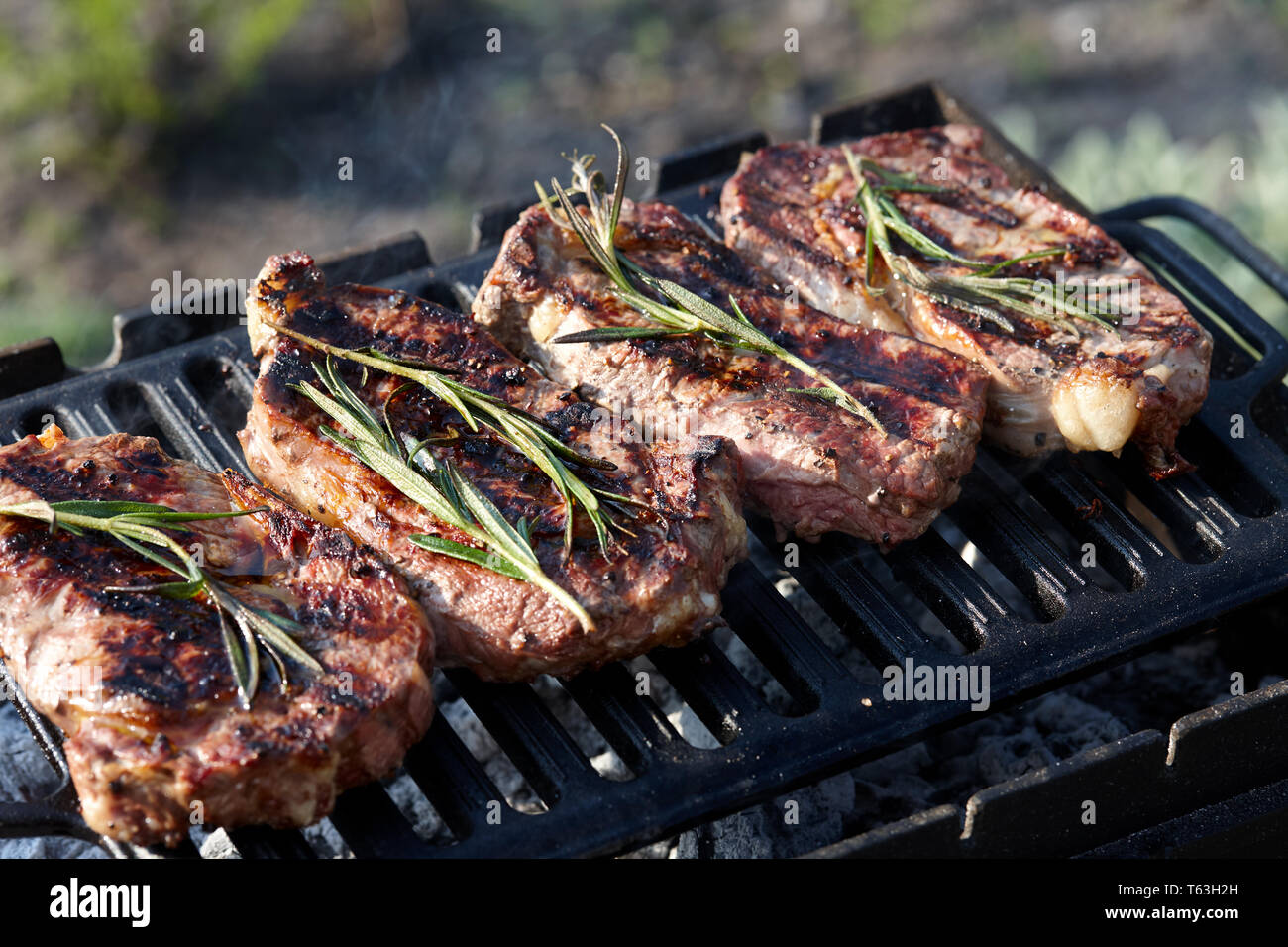 Juicy beef steaks cooking on grill outdoors Stock Photo - Alamy