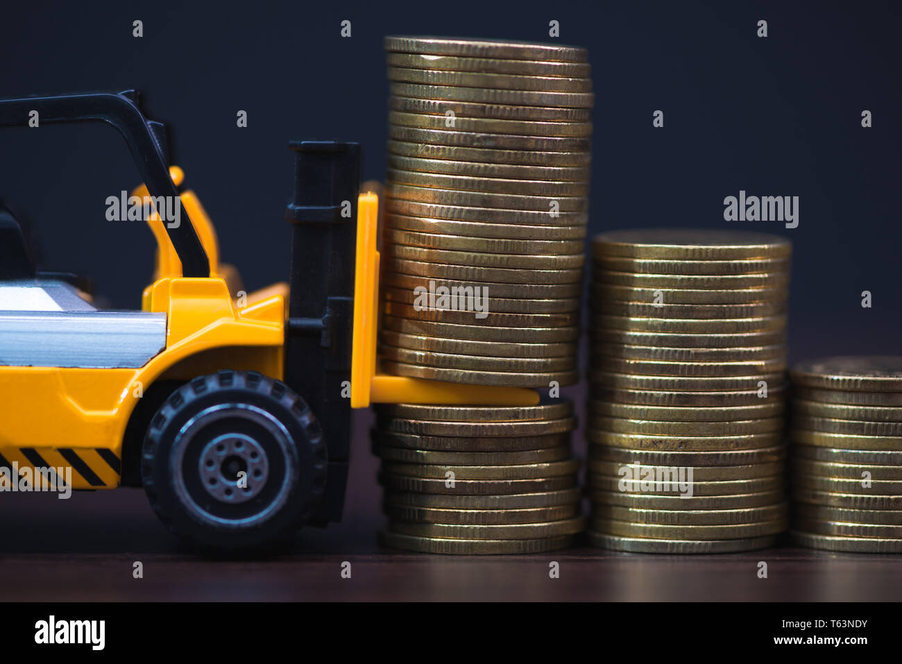 Mini forklift truck loading stack coin with steps of gold coin in dark ...