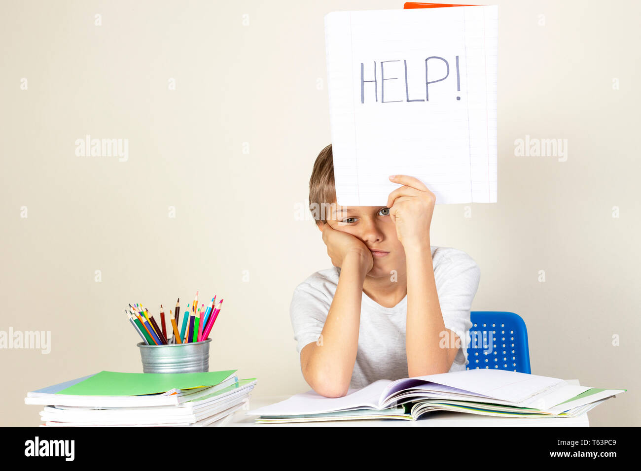 Help sign. Sad tired unhappy child doing homework and holding notebook ...