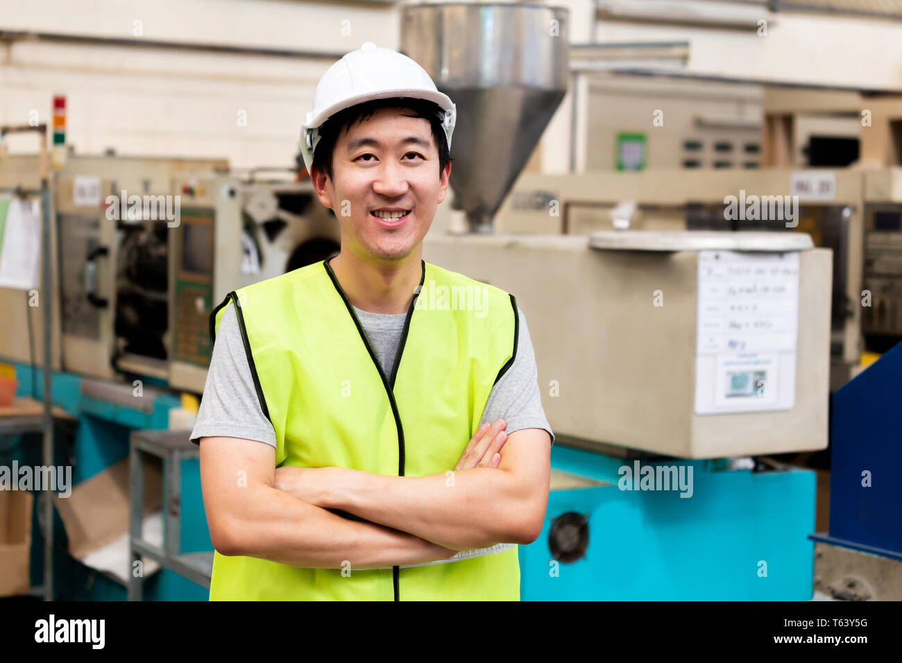 Front view of Asian factory worker with safety hard hat posed looking ...