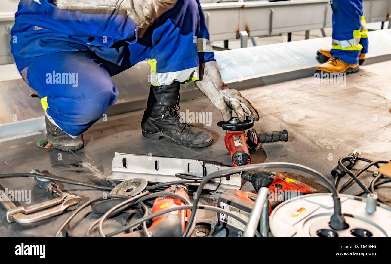 Worker using angle grinder on construction site Stock Photo - Alamy