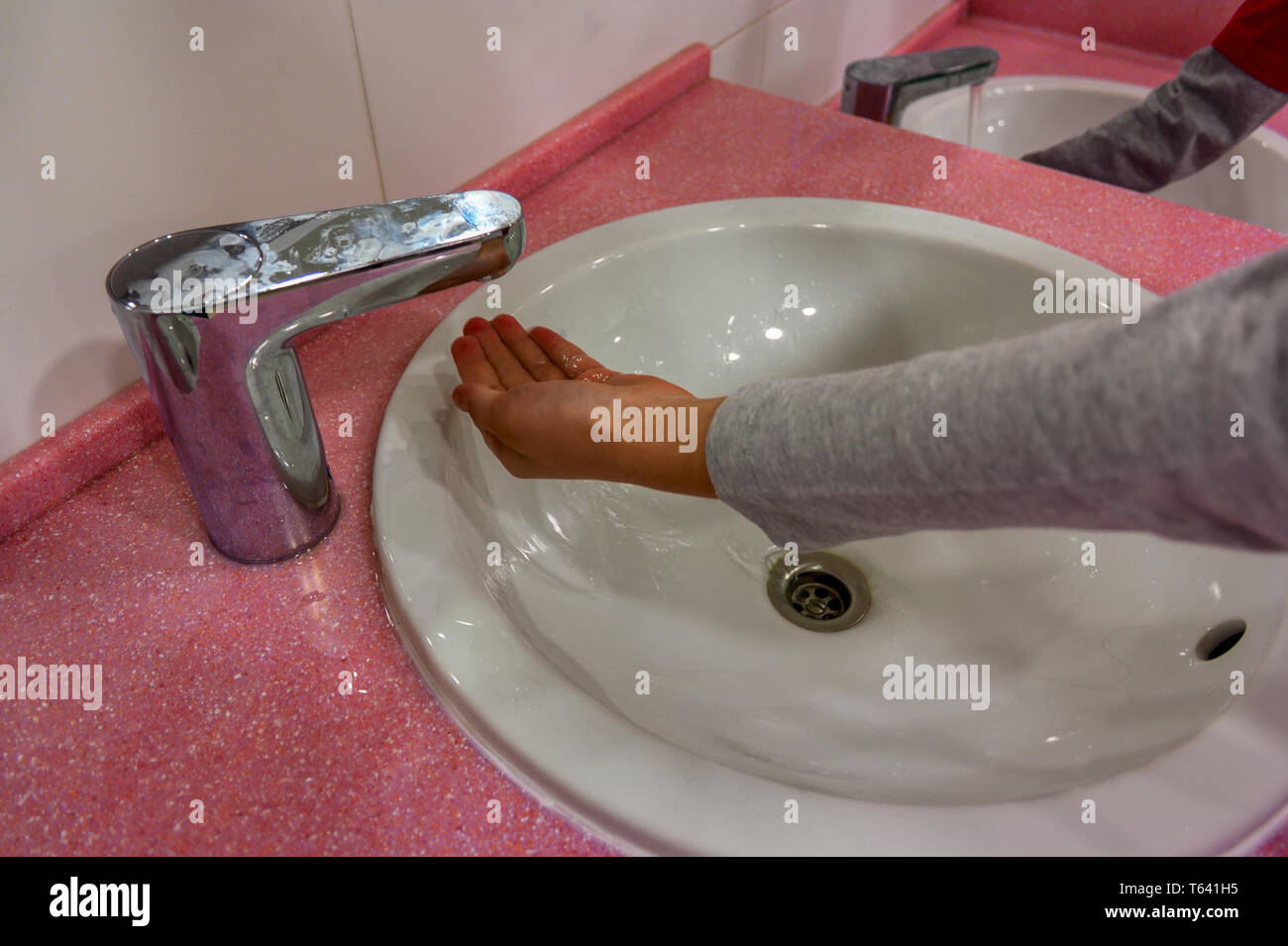 Children's hand under the tap from the mixer in the bathroom close-up ...