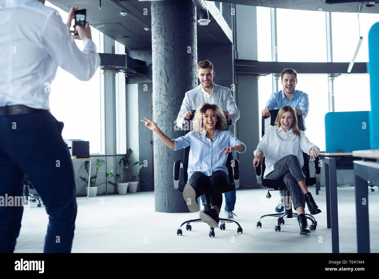 Positive colleagues having fun with office chairs Stock Photo - Alamy