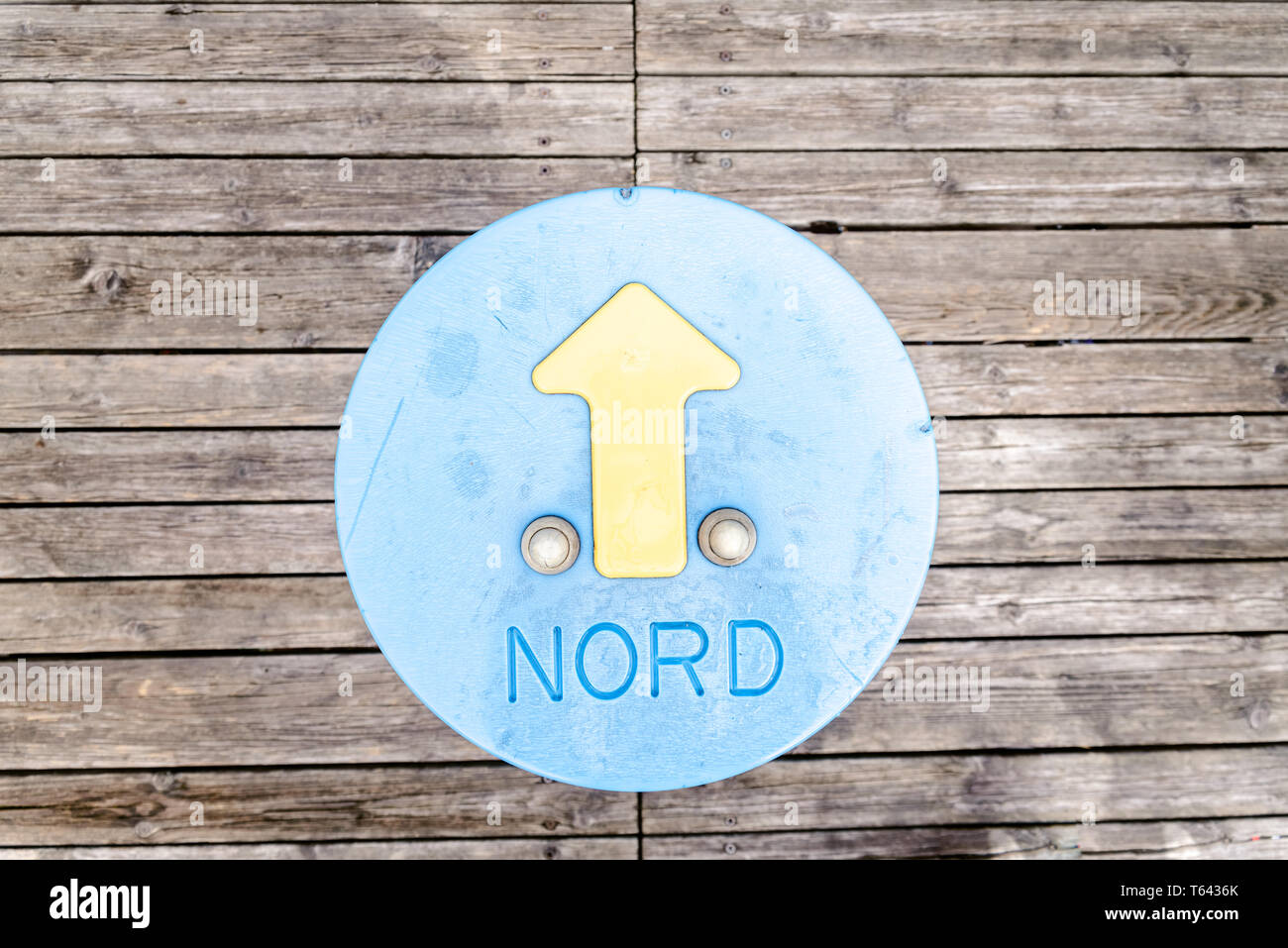 Nord word with direction arrow in a circle painted on wooden floor, for ...