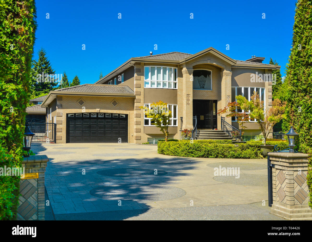 Front yard of luxury family house with paved driveway on blue sky ...