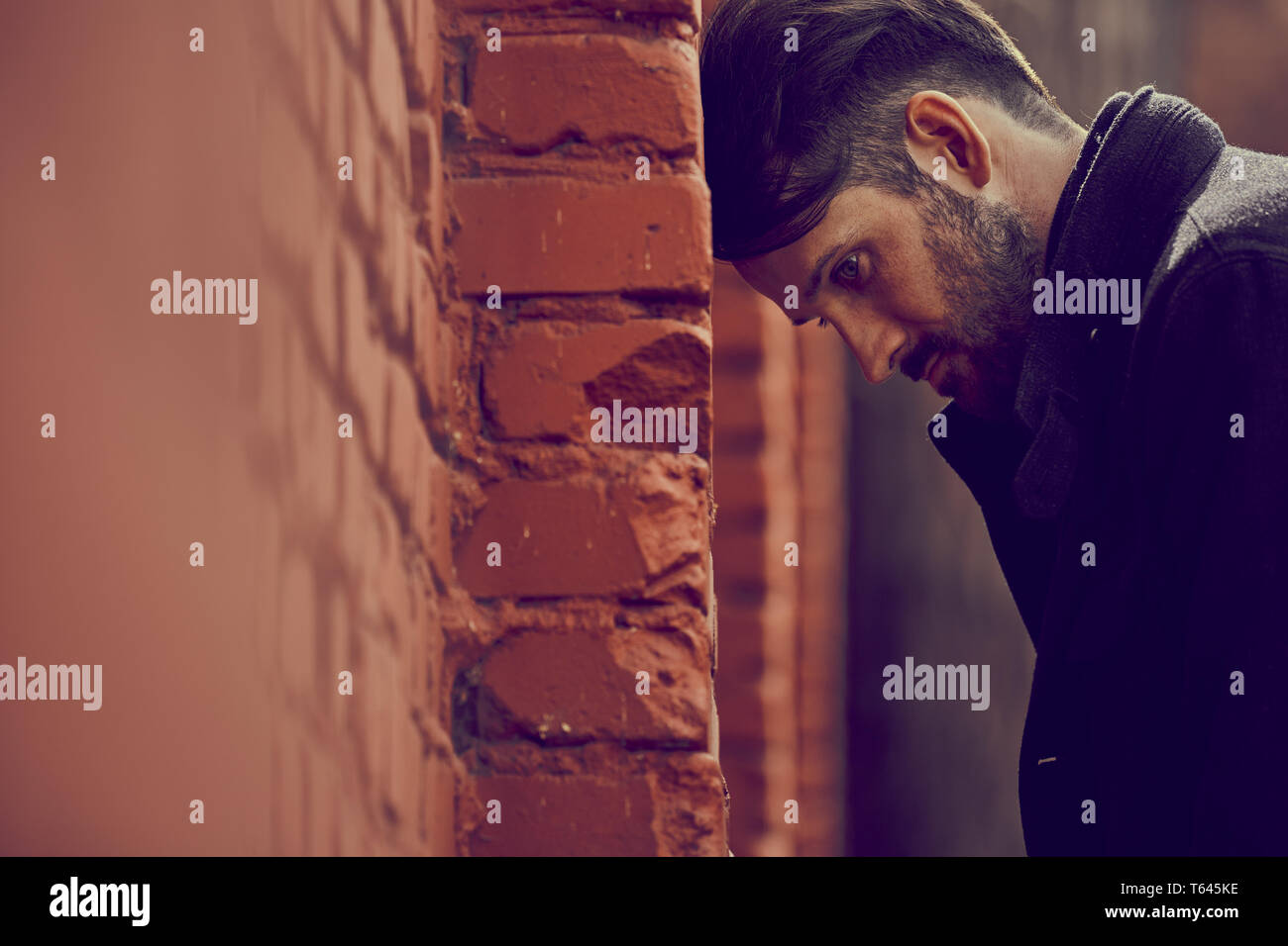 Frustrated depressed young man near the brick wall looking angry ...